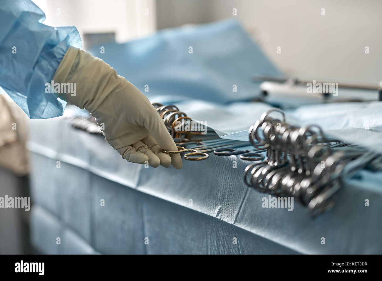 Hand in medical glove is taking a surgical forceps from the table in ...