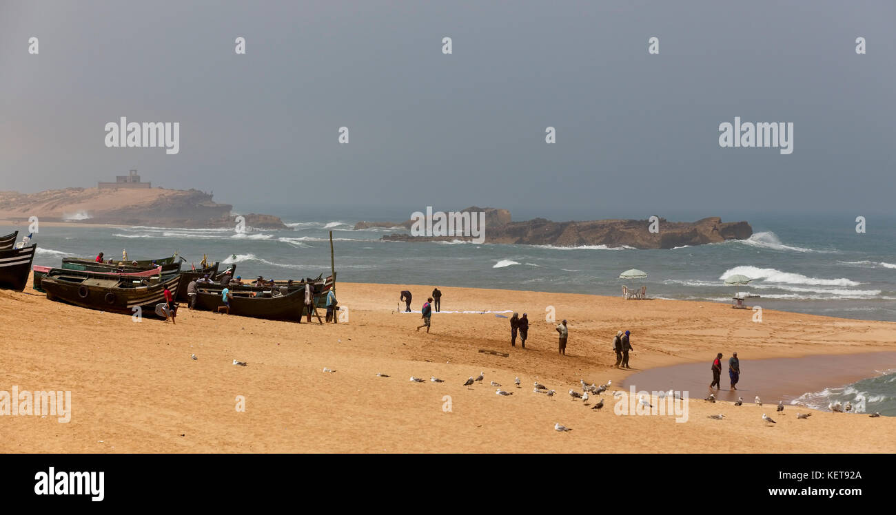Fishing boats, fishermen and gulls on a beach near Oualidia, Morocco ...