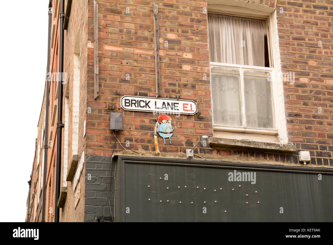 Brick Lane E1 street sign with modern art piece on wall beneath the ...