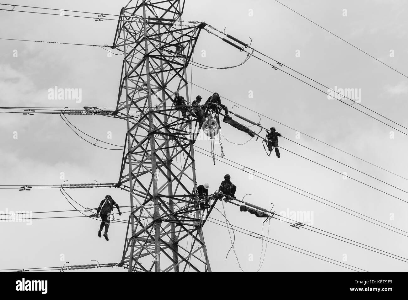 Electricians working on electrical cable power lines on steel tower ...