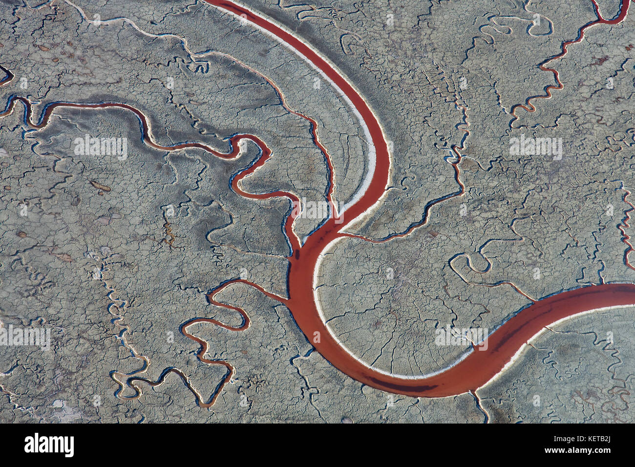A river turned red by microorganisms runs through salt ponds near San ...