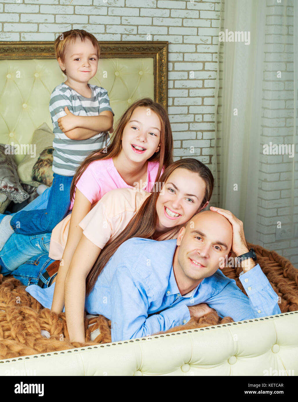 happy young parents with two kids in bed at home Stock Photo - Alamy