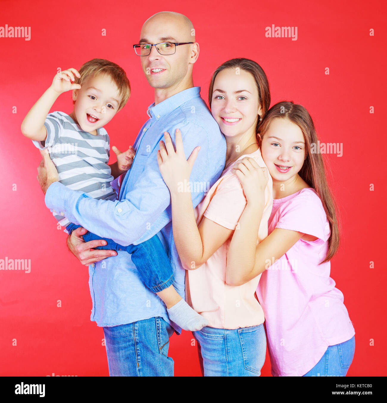 happy parents with two kids isolated against red background Stock Photo ...