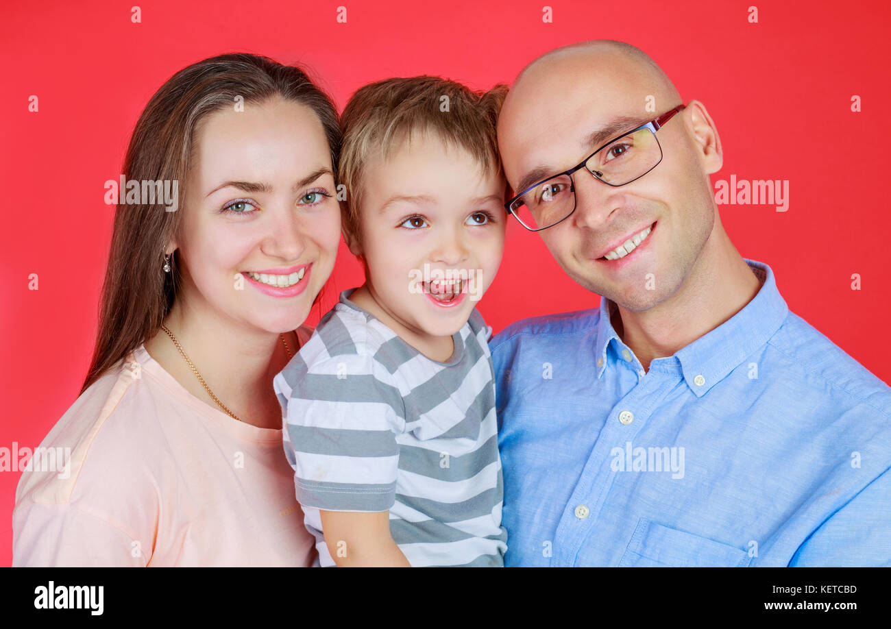 happy young parents with a little son isolated against red background ...