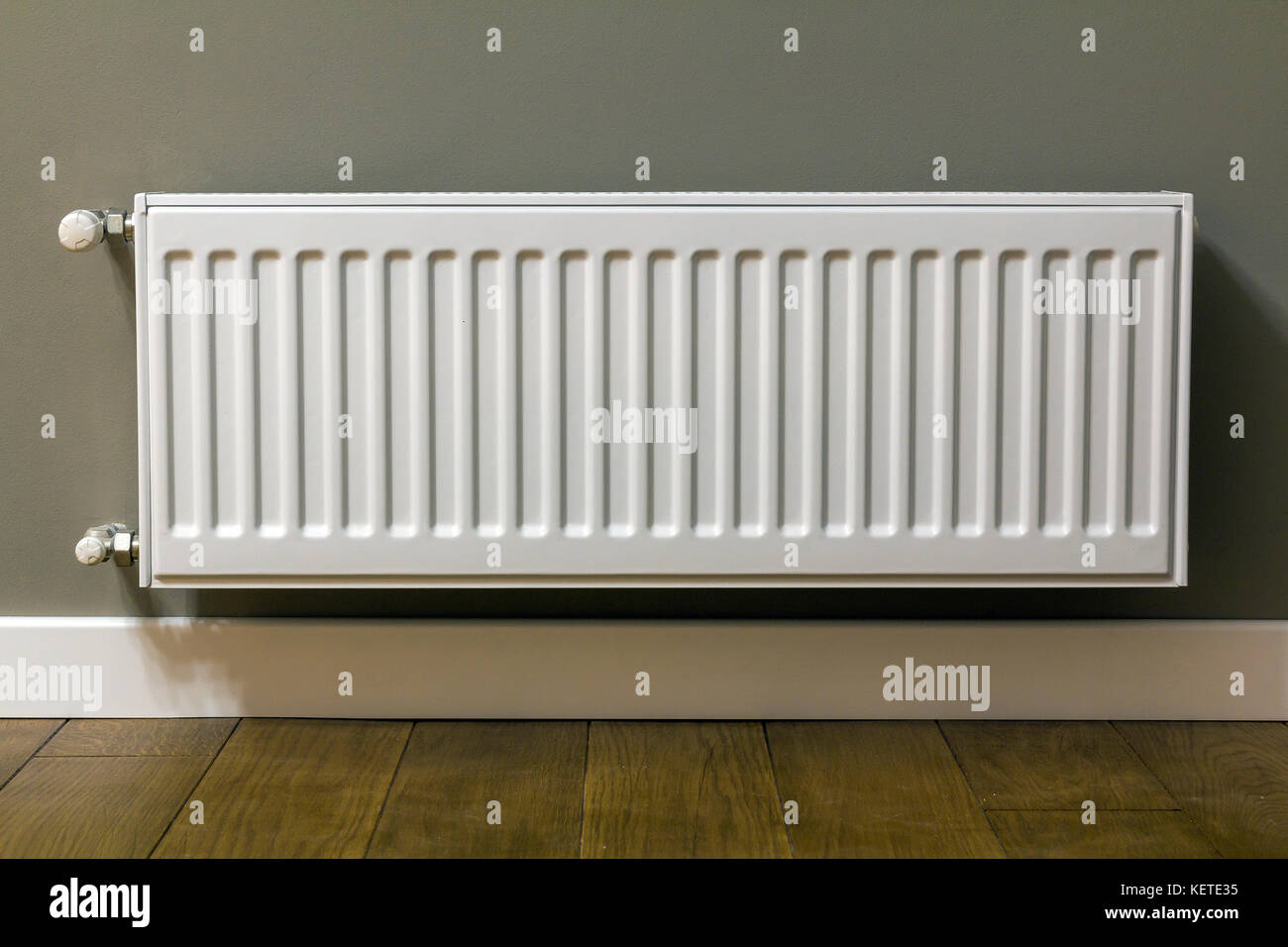 White heating radiator on wall in an apartment with wooden floor Stock ...