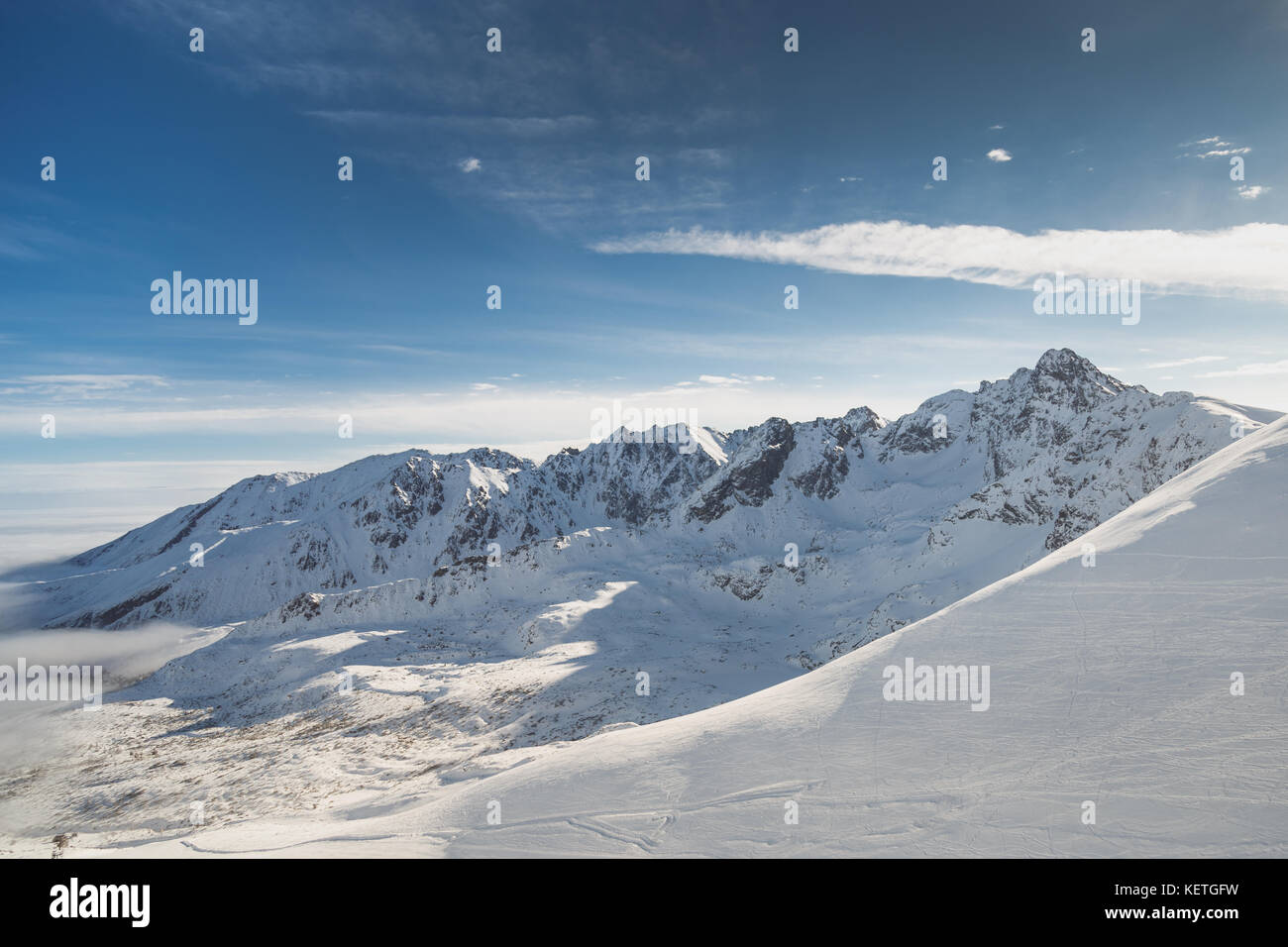 Wide shot aerial view of snow capped cold rock mountains with sunny ...
