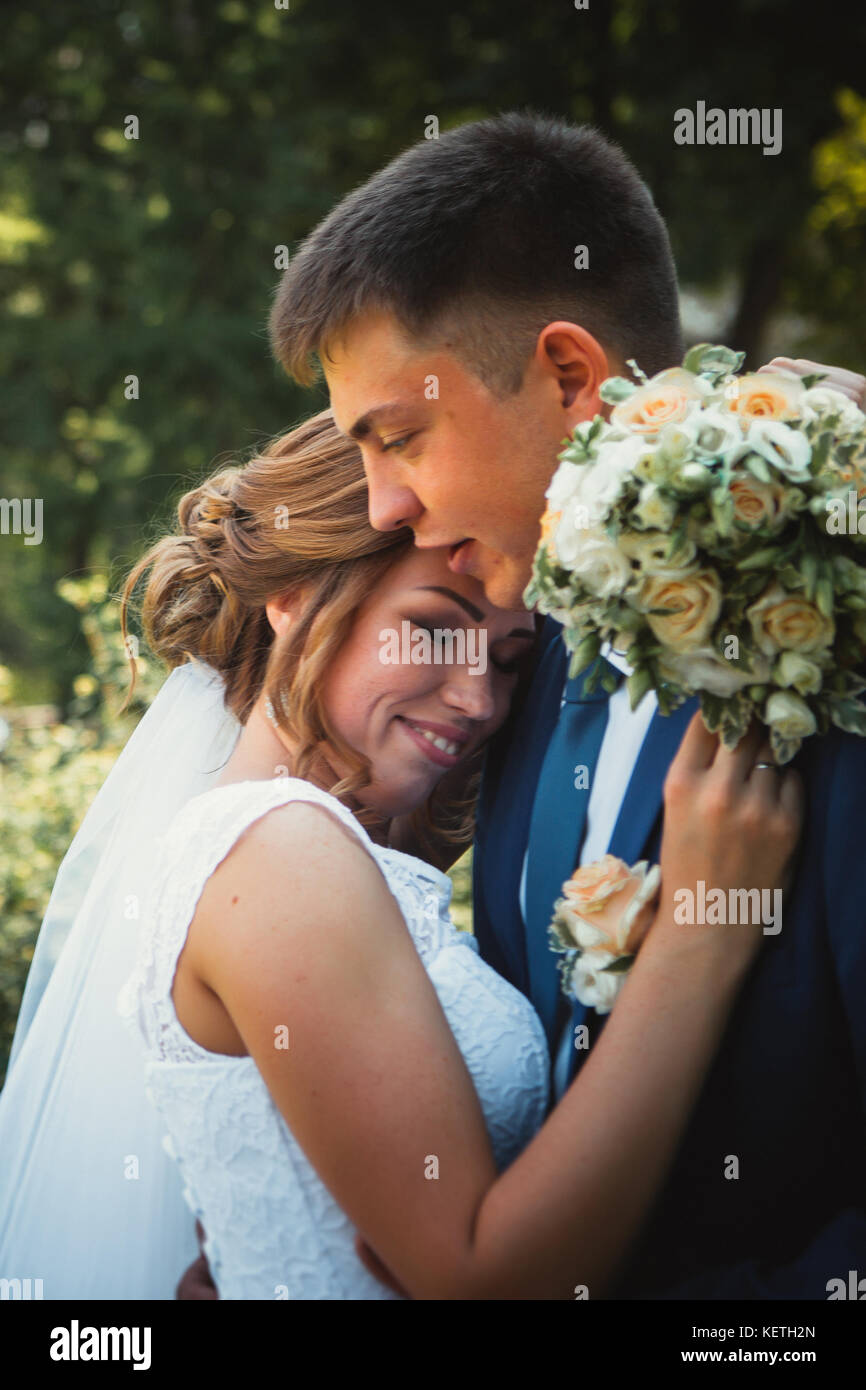 couple groom and bride hugging and kissing on nature park background ...