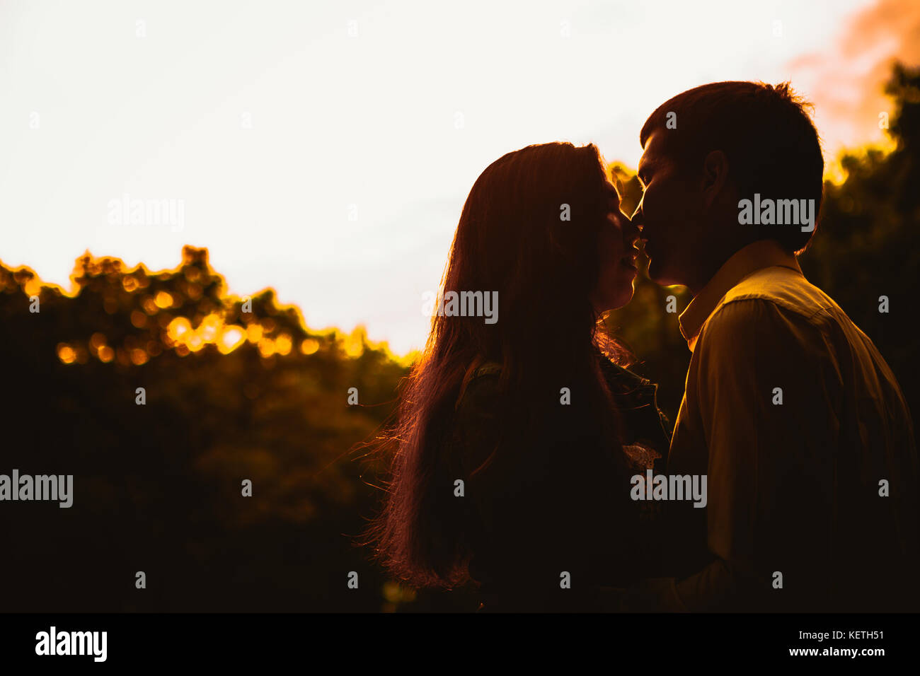 Beautiful young couple on the sunset background Stock Photo - Alamy