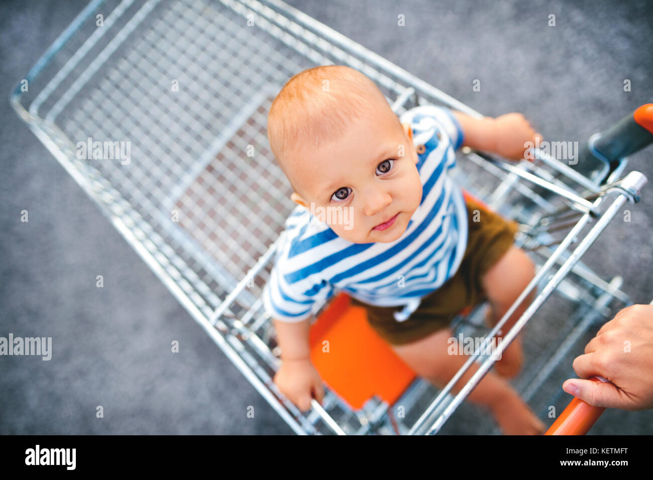 Baby boy sitting in the shopping trolley outside Stock Photo - Alamy