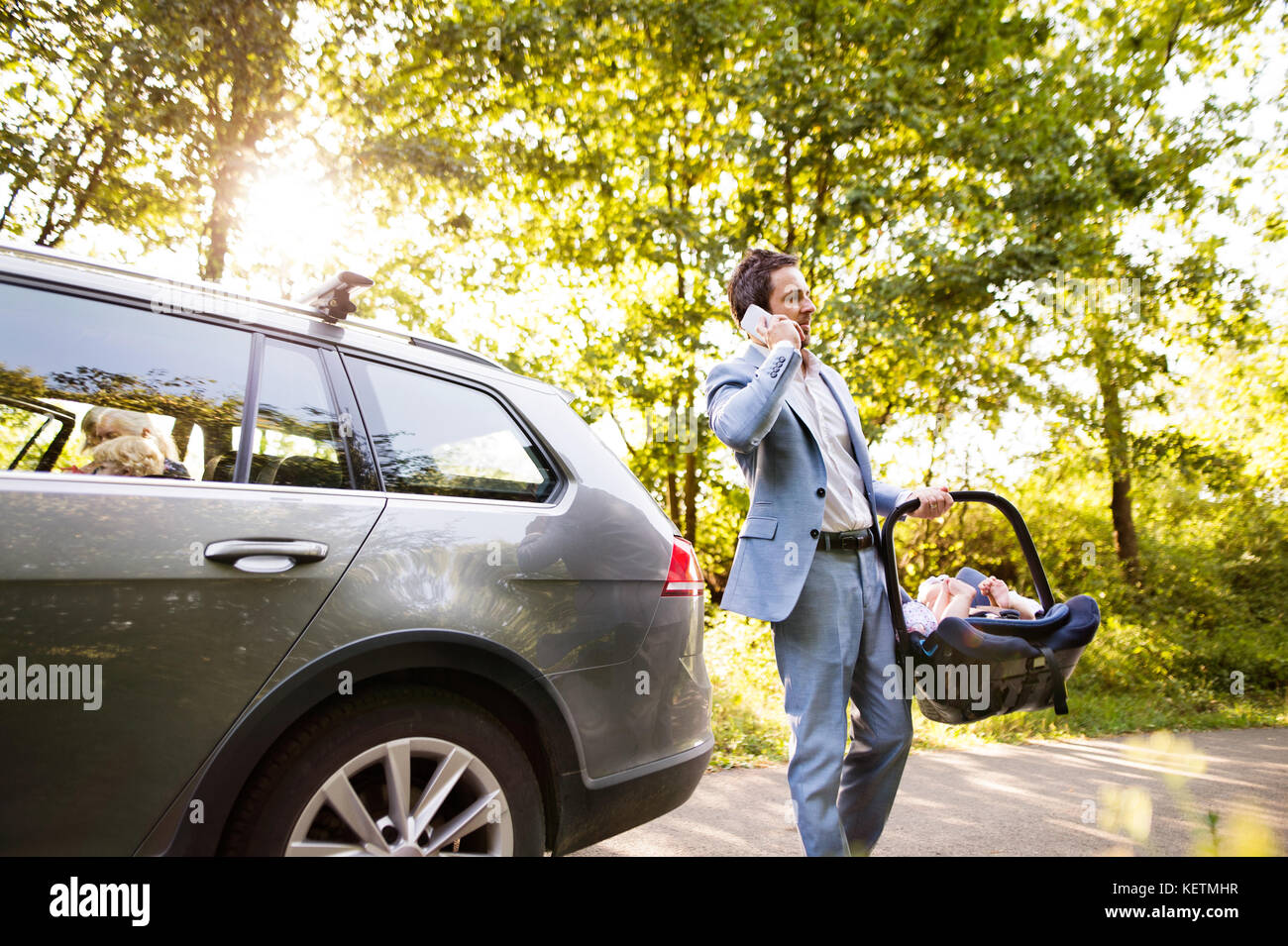 Young father with a smartphone going into the car with his baby Stock ...