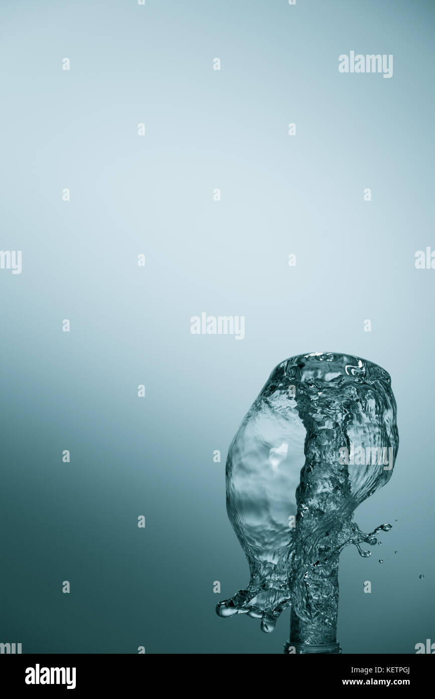 A stream of filtered natural water on a blue background. Splash of ...