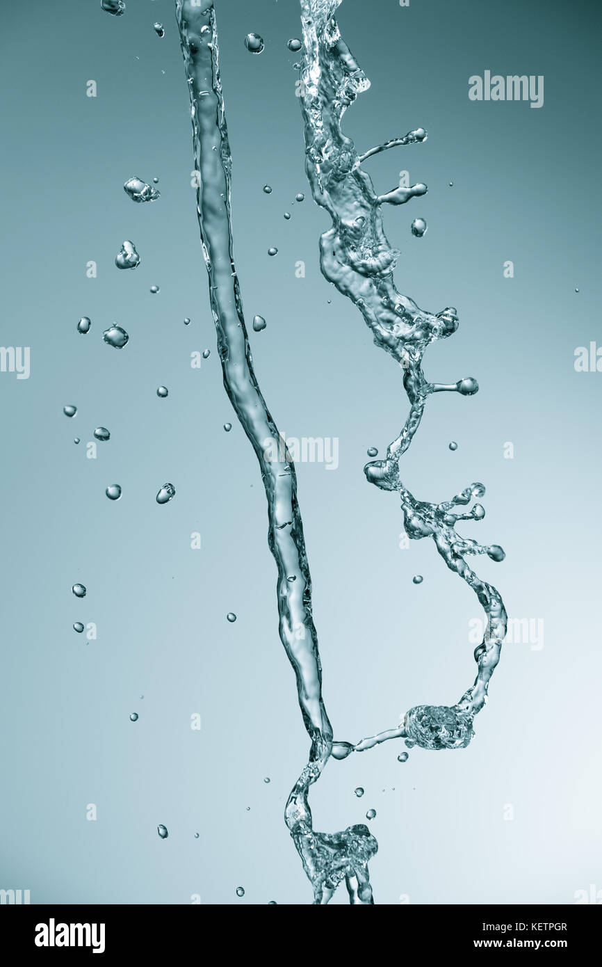 A stream of filtered natural water on a blue background. Splash of ...