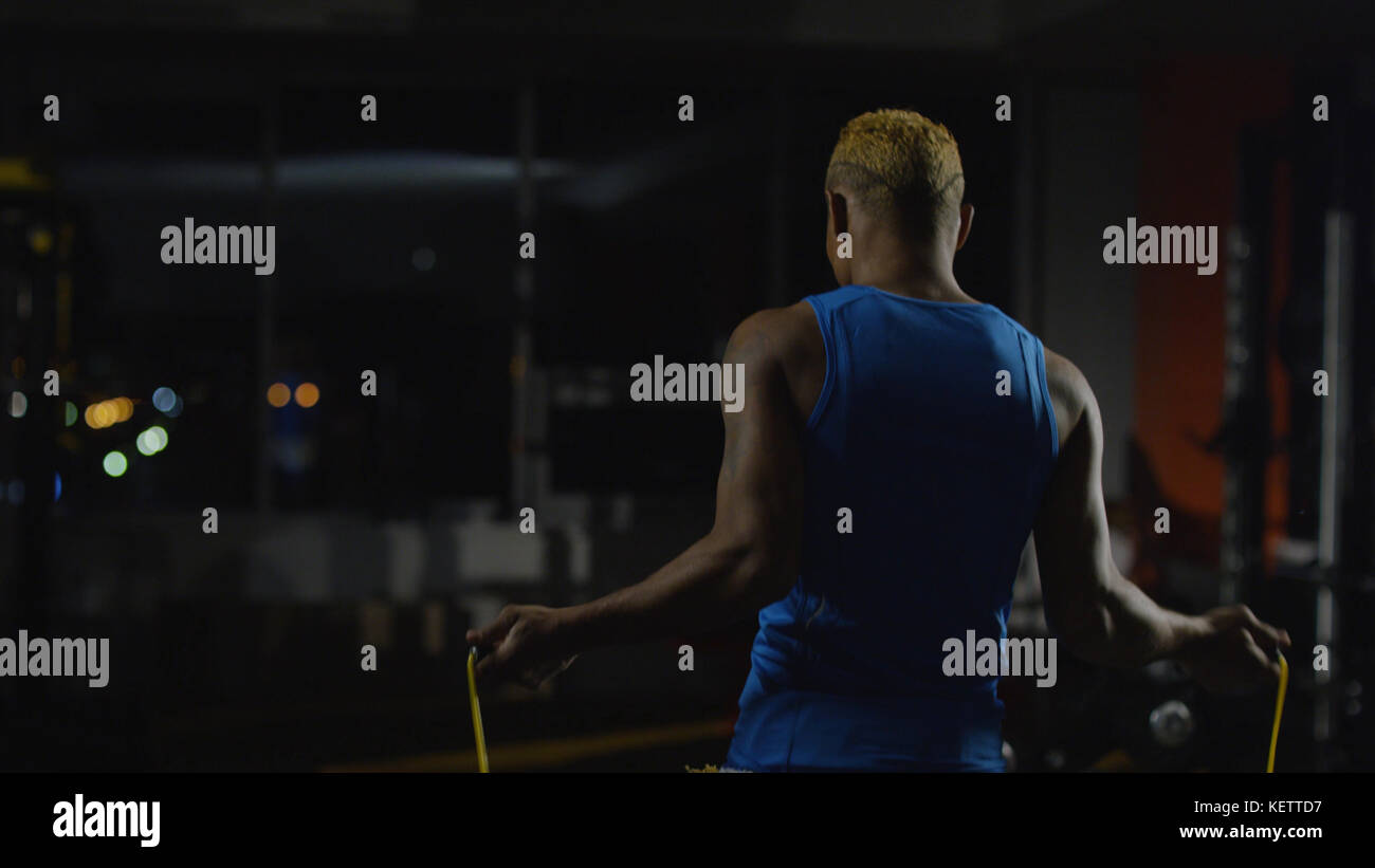 Full length portrait of a boxer jumping with skipping rope. Athletic ...