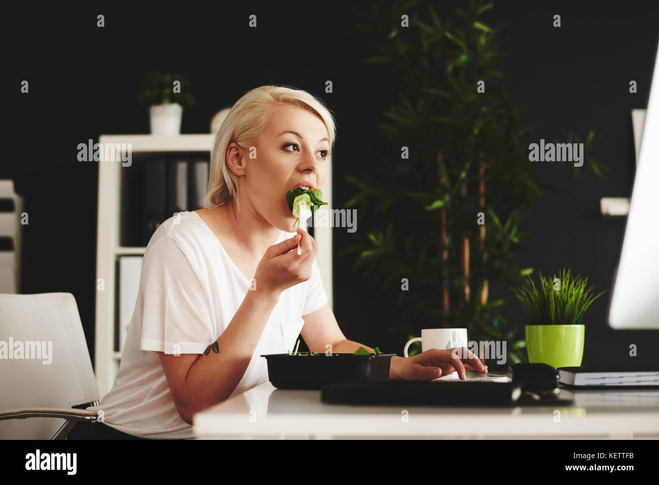 Multipurpose woman eating and using a computer at office Stock Photo ...