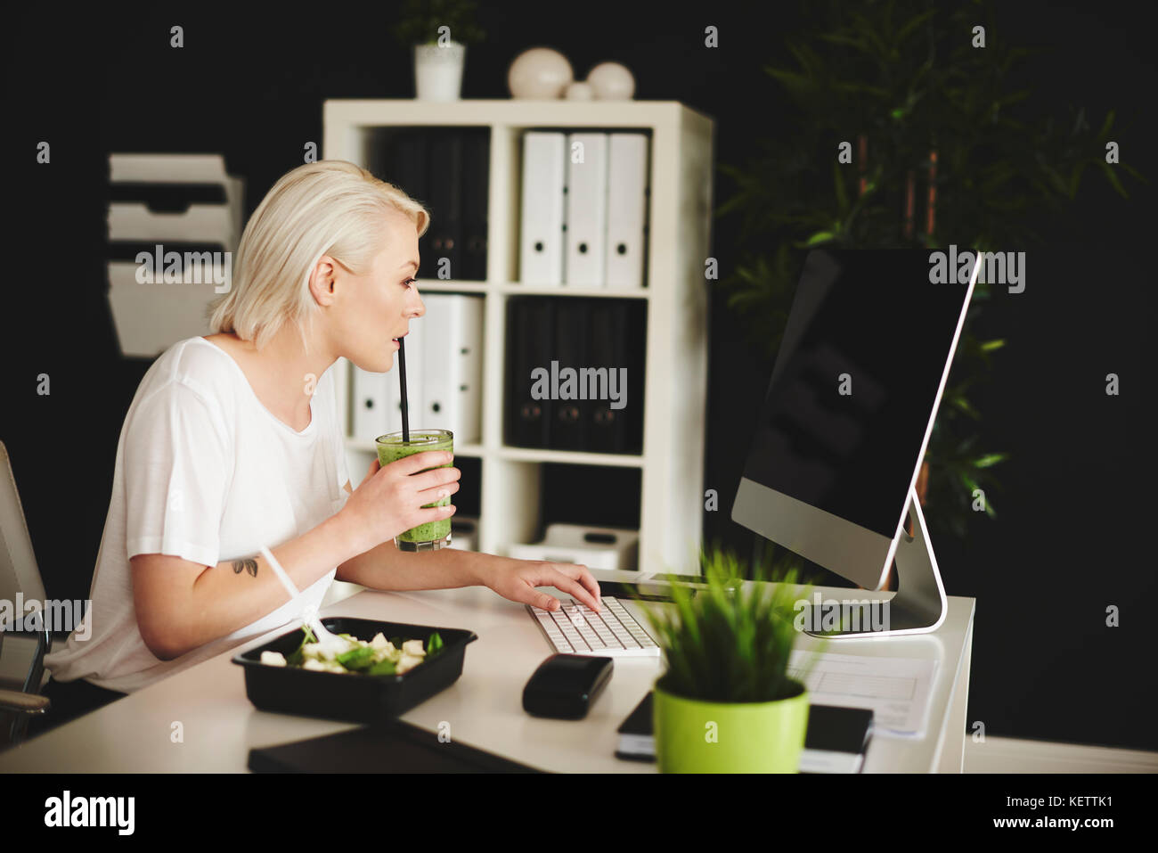 Woman drinking smoothie and working with a computer Stock Photo - Alamy