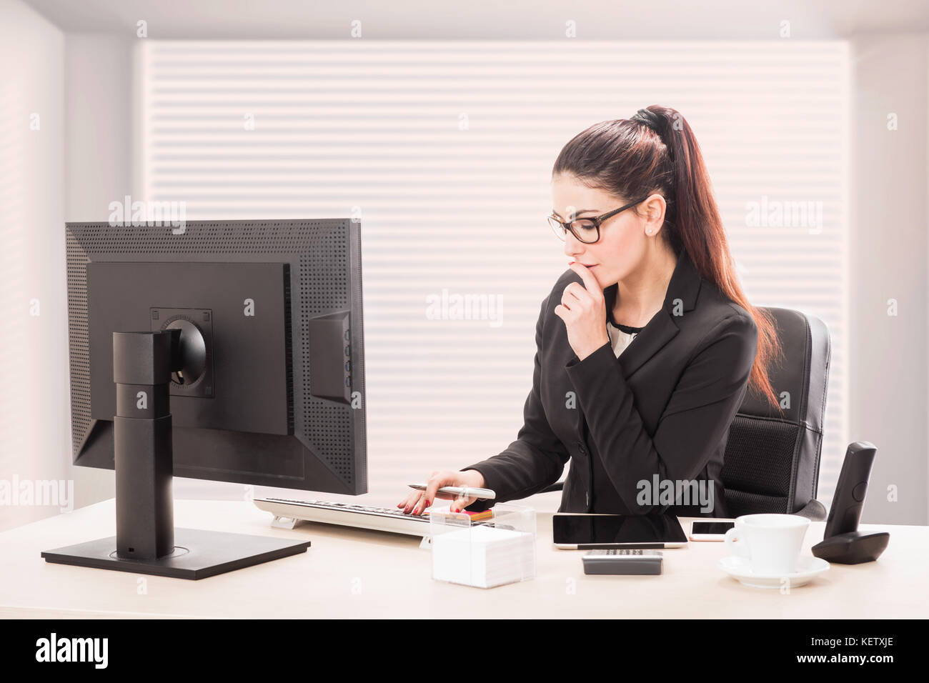 Portrait of a pretty secretary sitting at her desk Stock Photo - Alamy