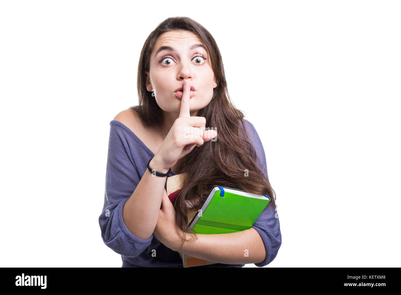 Cute young girl student making silence gesture and holding books on ...