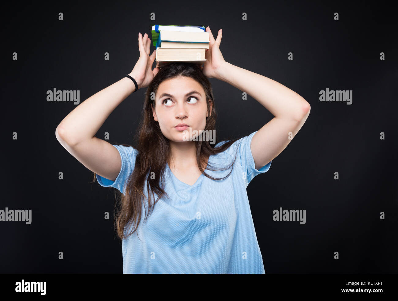 Young college student holding stack of books on top of her head ...