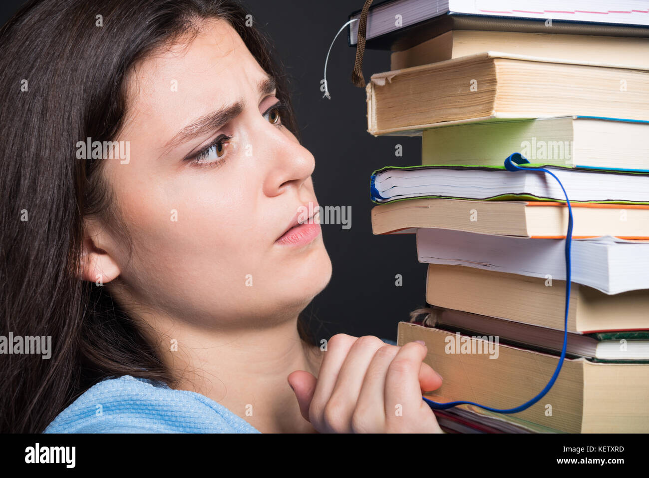 Sad young student holding many books and learning for school exams ...