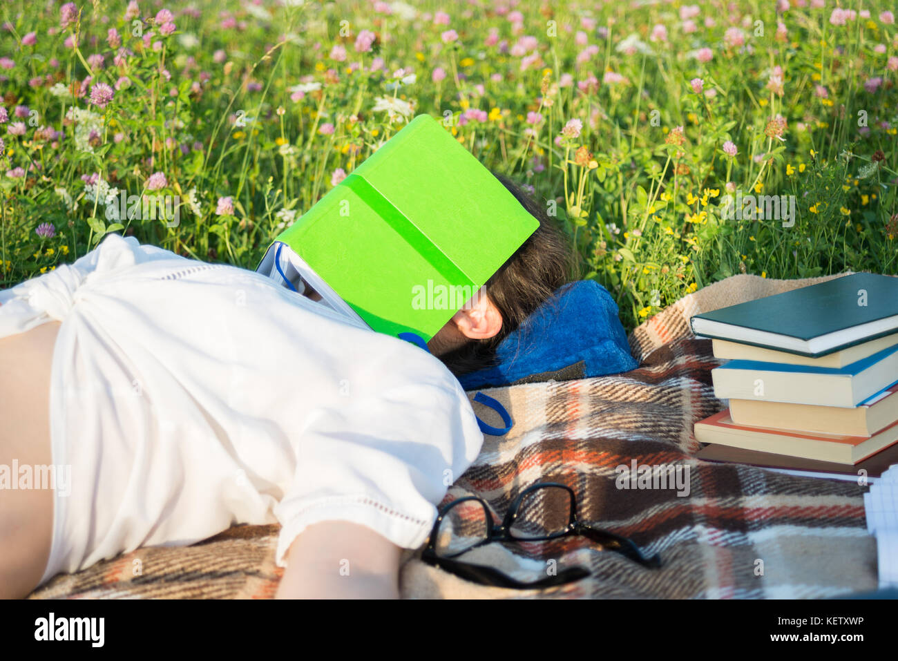 Woman sleeping on the grass outside while reading a book Stock Photo ...