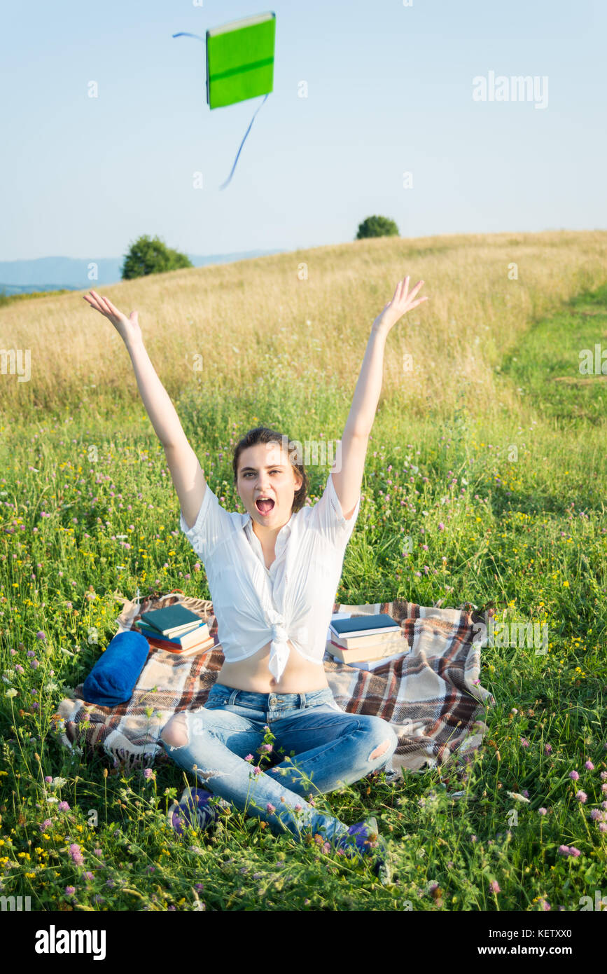 Cheerful pretty female throwing her book in the air feeling happy and ...