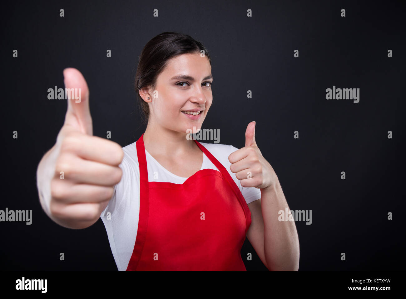 Smiling supermarket seller gesturing thumbs up with both hands and ...