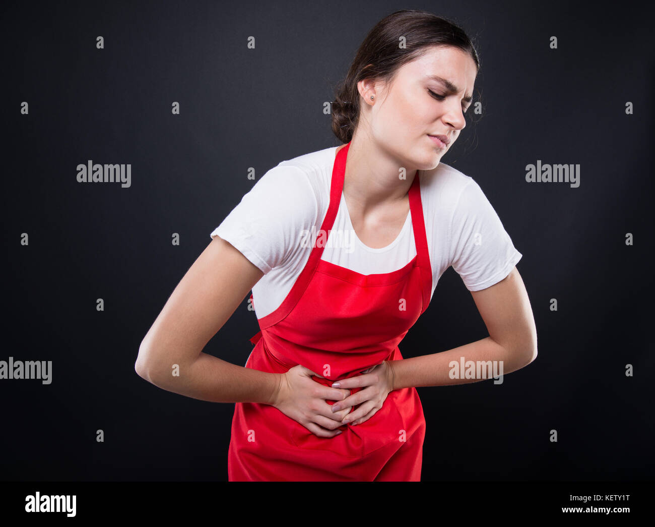 Beautiful hypermarket girl with apron feeling pain in her belly after ...
