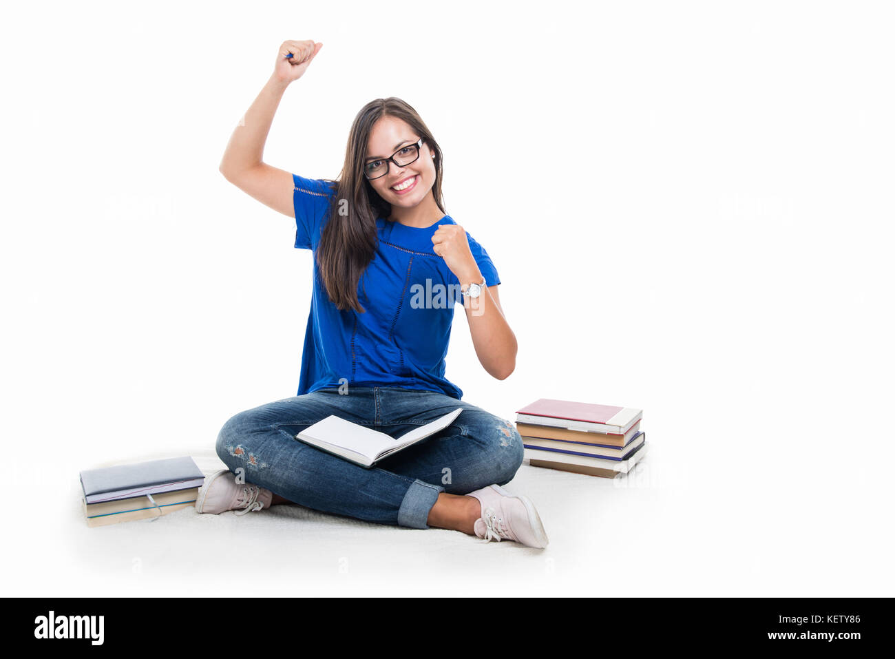 Beautiful student girl sitting making winner gesture with books around ...
