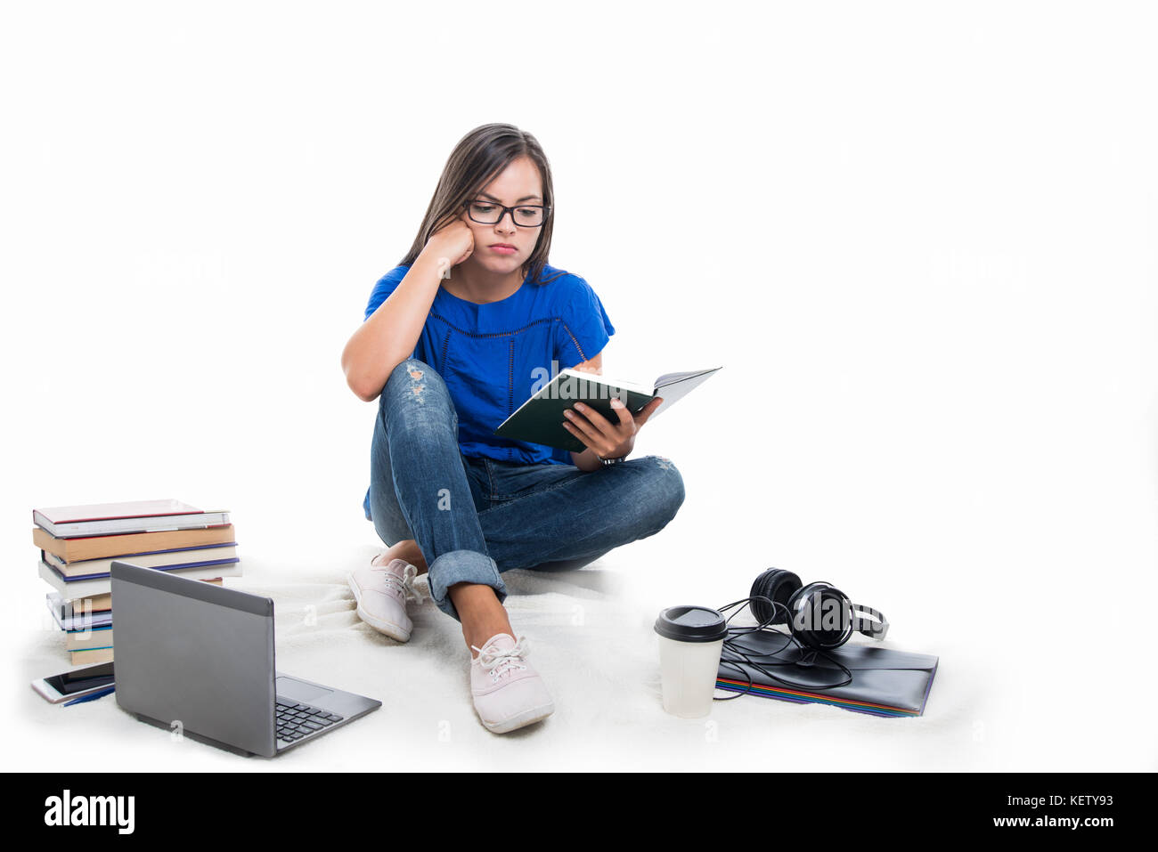 Student sitting down bored looking in notebook with books around ...