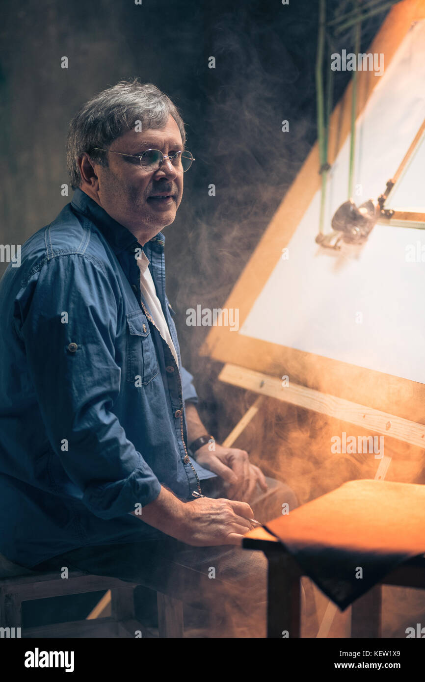 The mature creative engineer working with project on drawing board ...