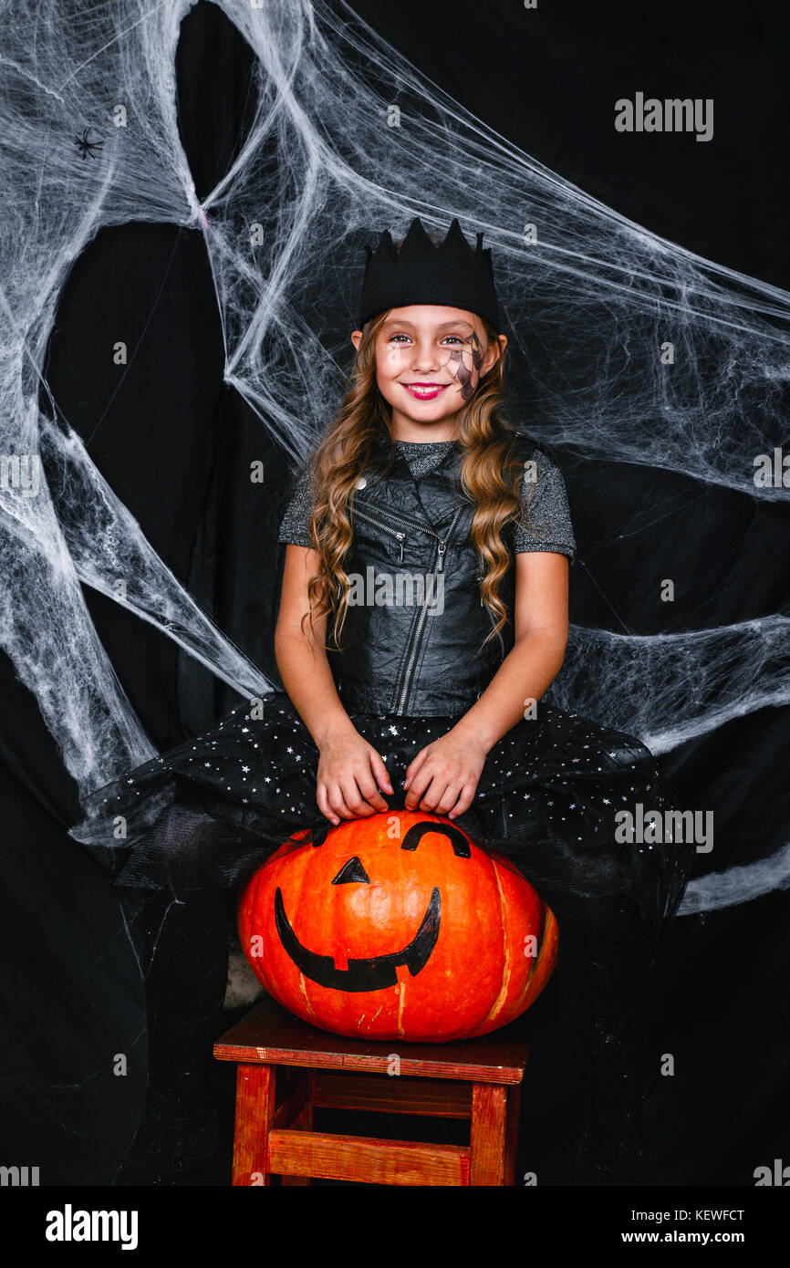 Cute little girl in halloween costume sitting on the pumpkin on ...
