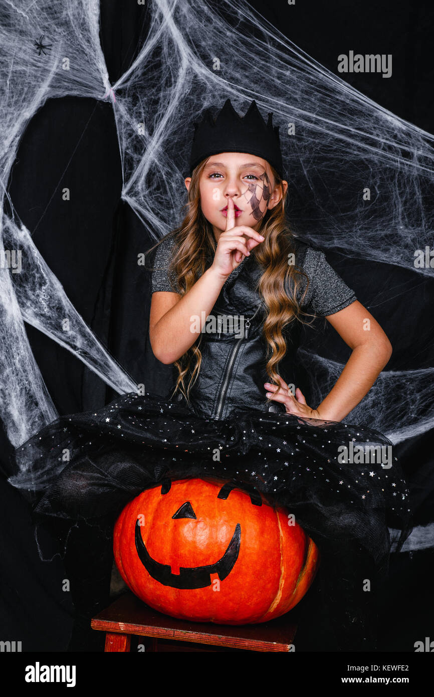 Cute little girl in halloween costume sitting on the pumpkin on ...