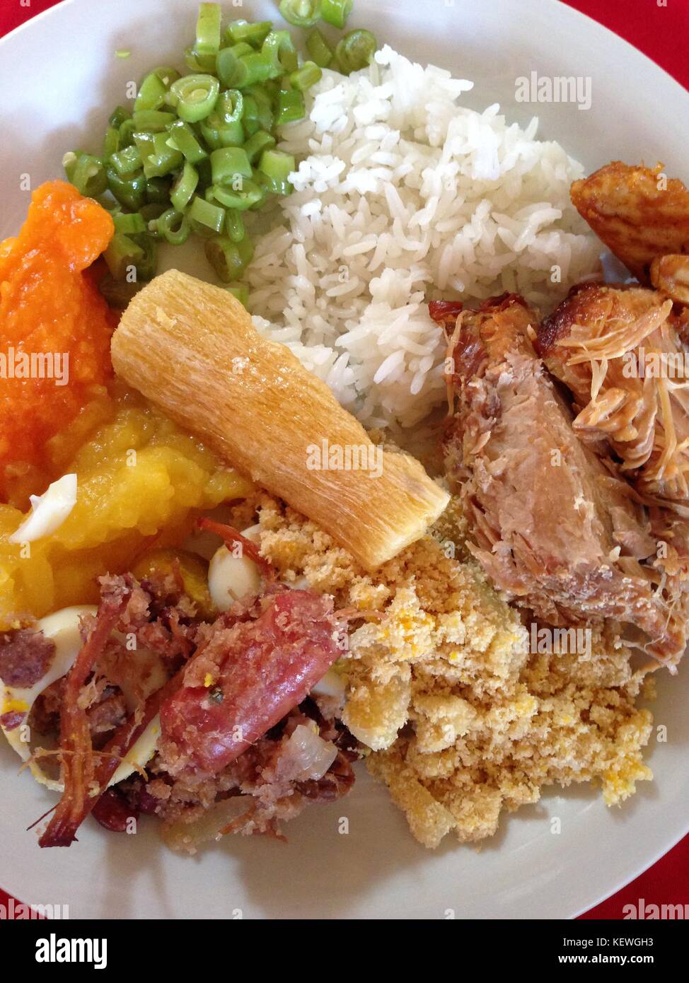 Colorful brazilian plate with rice, farofa, cassava, pork and ...