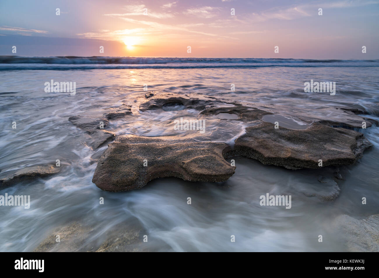Sunrise over the Incoming tide swirling around a coquina rock at ...