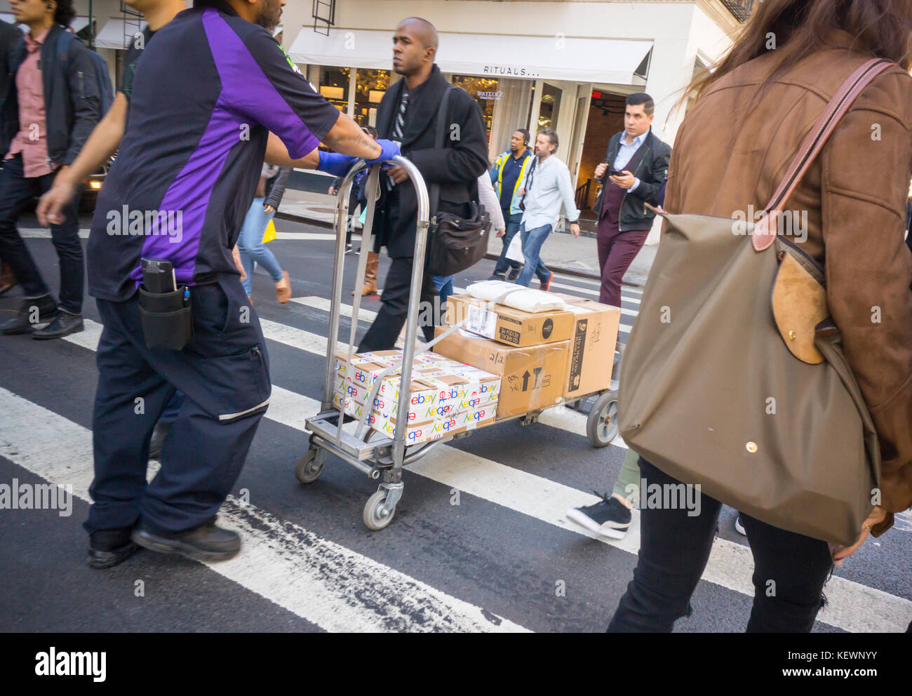 A FedEx worker in New York in a busy crosswalk delivering packages on ...