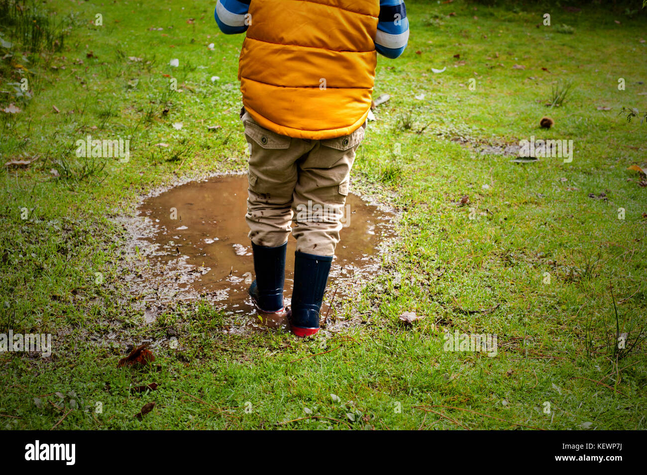 Boy having fun splashing in muddy puddles Stock Photo - Alamy