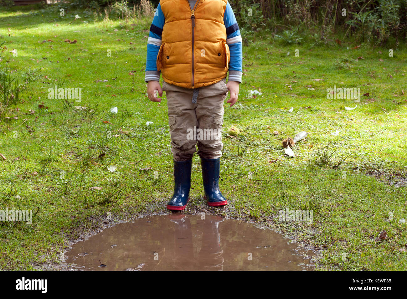 Boy having fun splashing in muddy puddles Stock Photo - Alamy