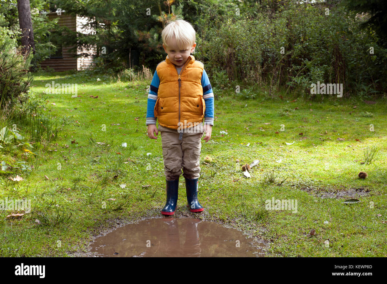 Boy having fun splashing in muddy puddles Stock Photo - Alamy