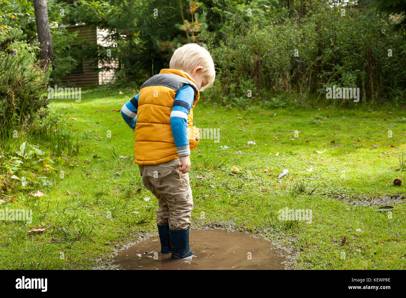 Boy having fun splashing in muddy puddles Stock Photo - Alamy