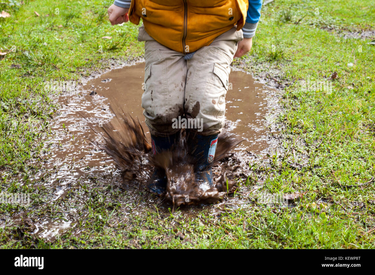 Boy having fun splashing in muddy puddles Stock Photo - Alamy