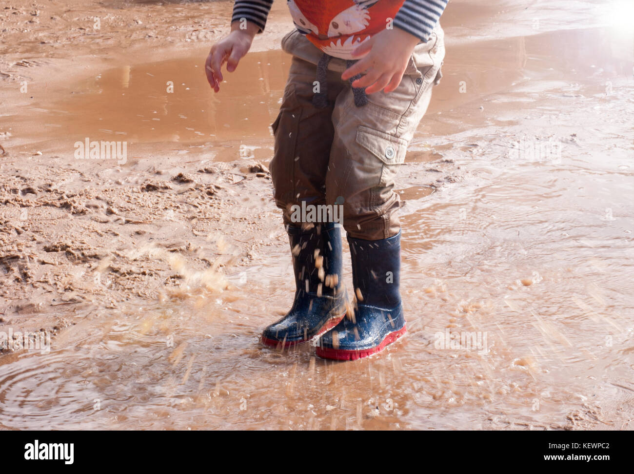 Boy having fun splashing in muddy puddles Stock Photo - Alamy