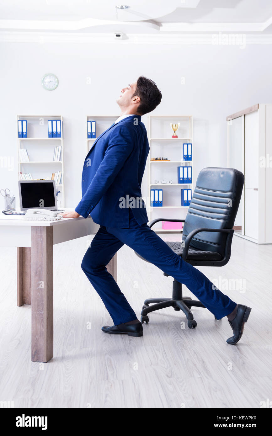 Young businessman doing sports stretching at workplace Stock Photo - Alamy
