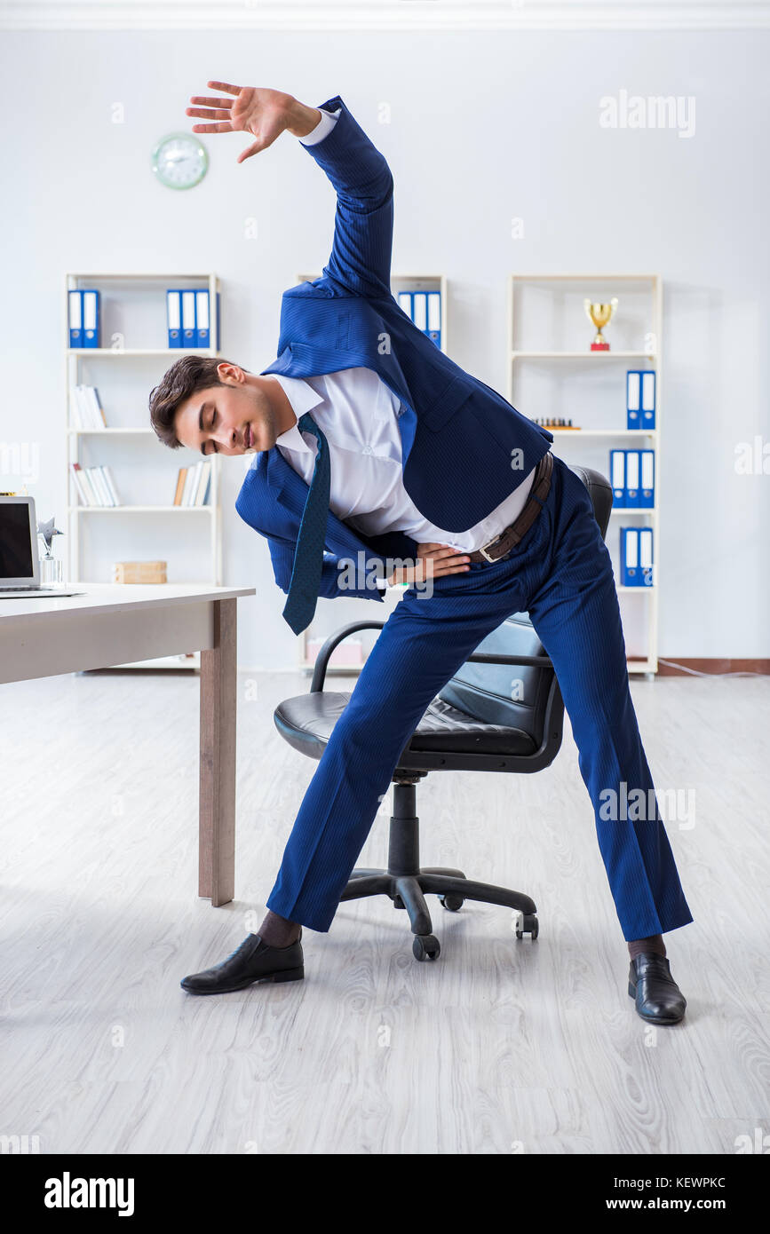 Young businessman doing sports stretching at workplace Stock Photo - Alamy