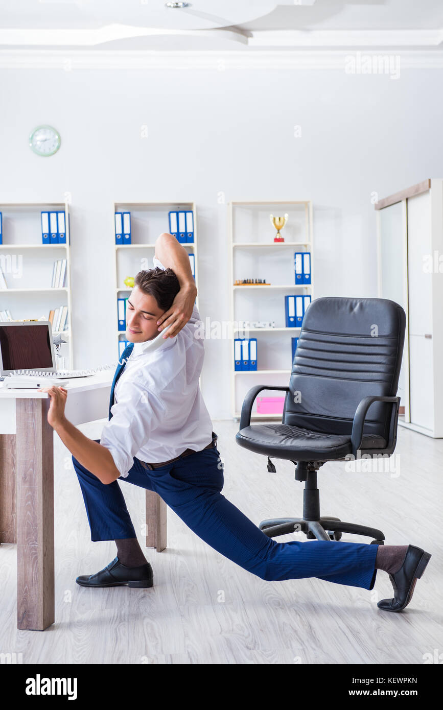 Young businessman doing sports stretching at workplace Stock Photo - Alamy