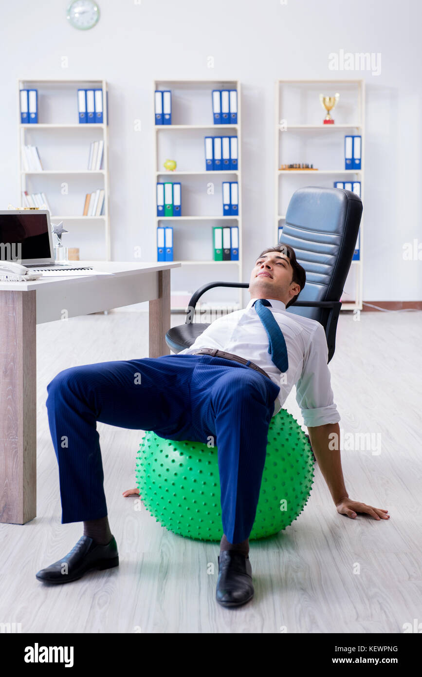 Young businessman doing sports stretching at workplace Stock Photo - Alamy