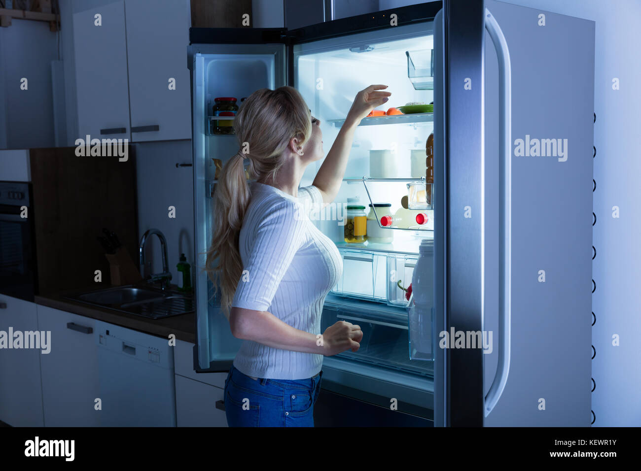 Young Woman Searching For Food Standing Near Refrigerator In Kitchen ...