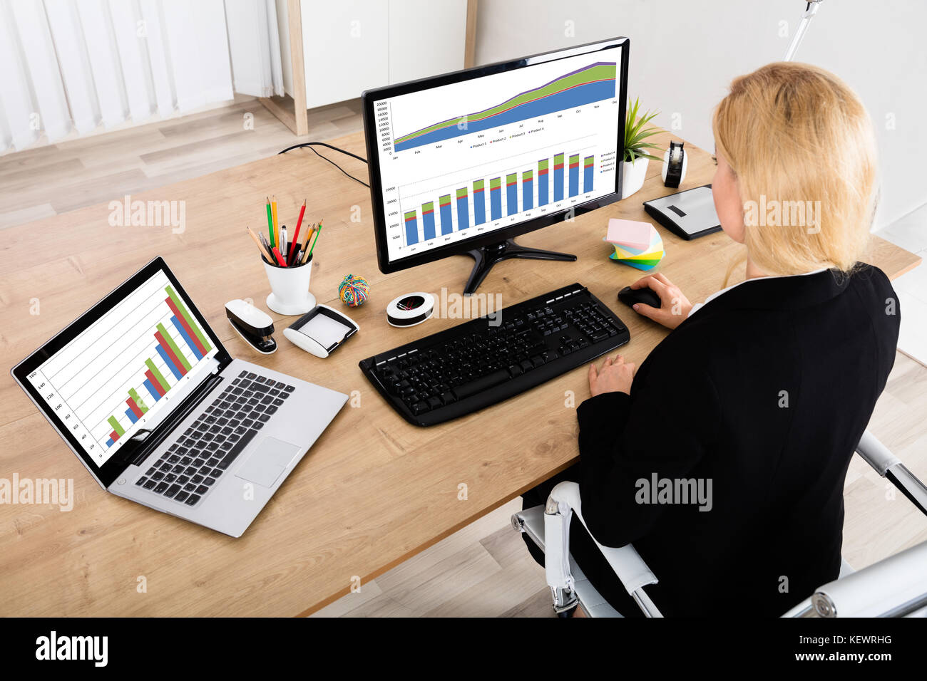 A Businesswoman Analyzing Graph On Computer And Laptop In Office Stock ...