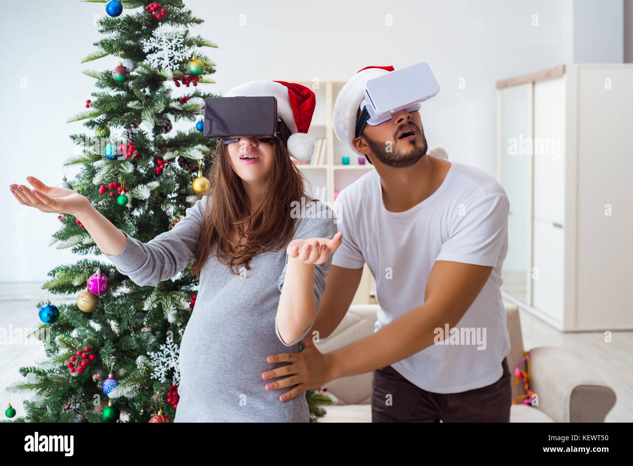 Young family expecting child baby wearing virtual reality VR glasses ...