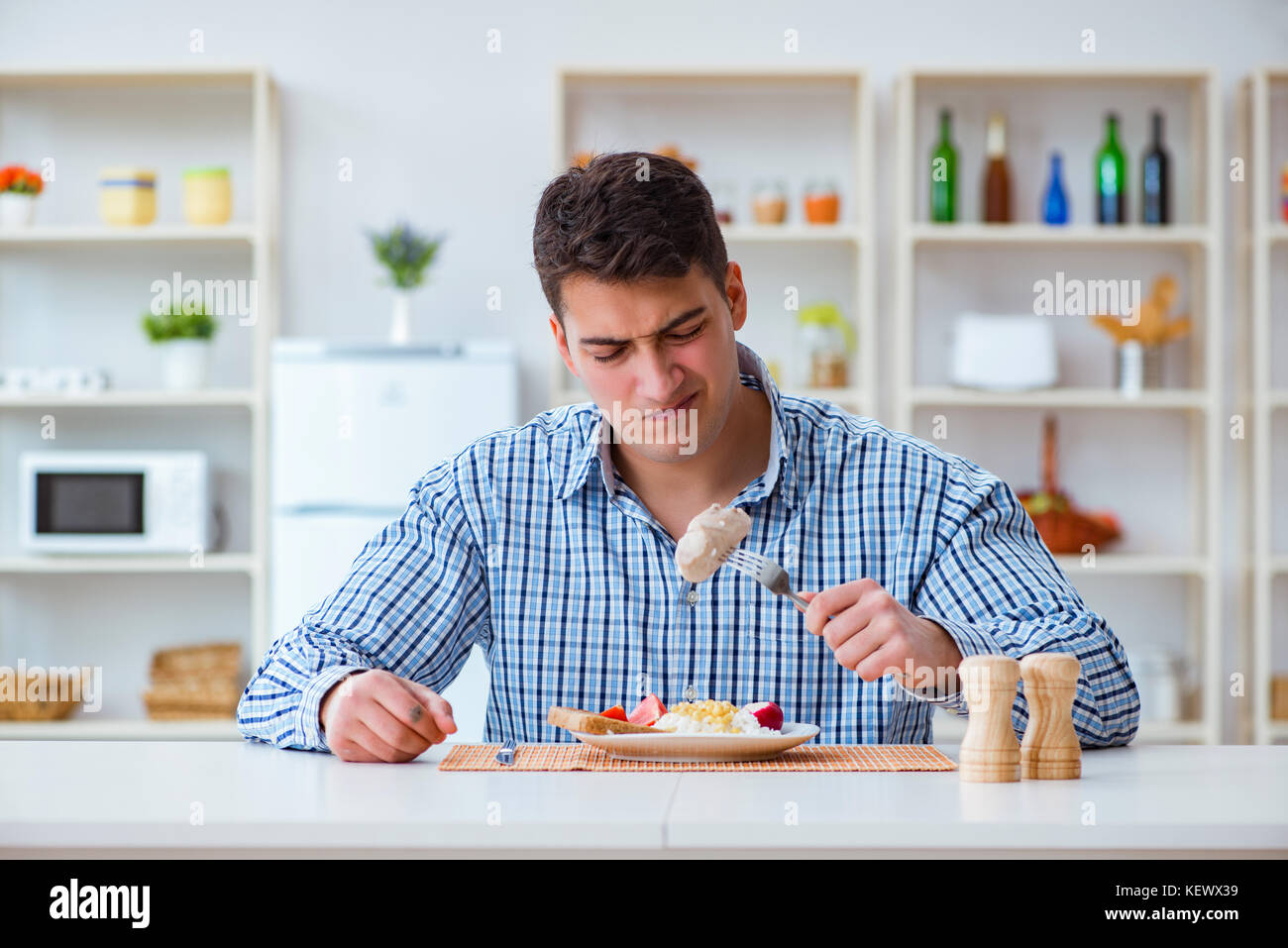 Man eating tasteless food at home for lunch Stock Photo - Alamy
