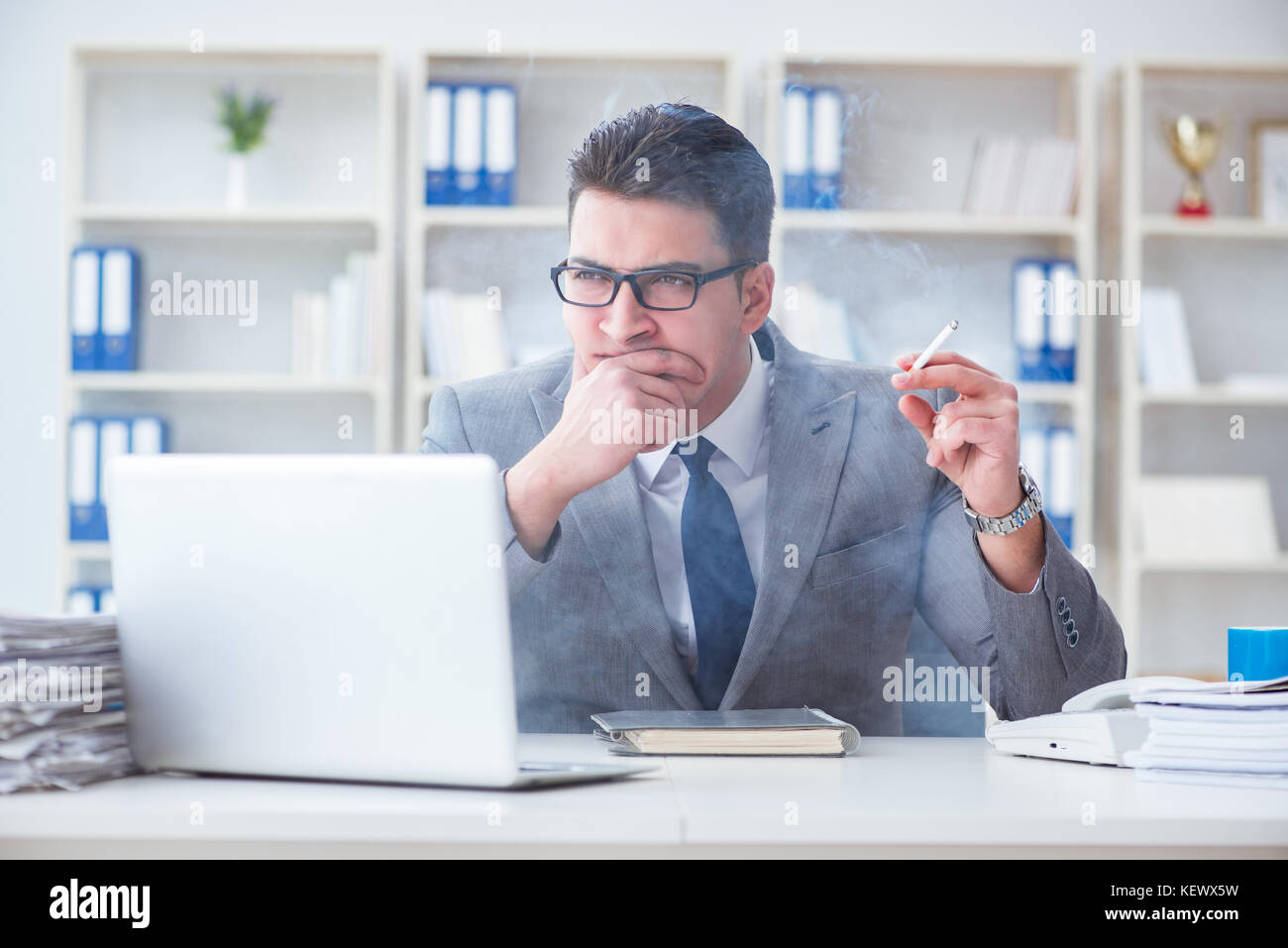 Businessman smoking in office at work Stock Photo - Alamy